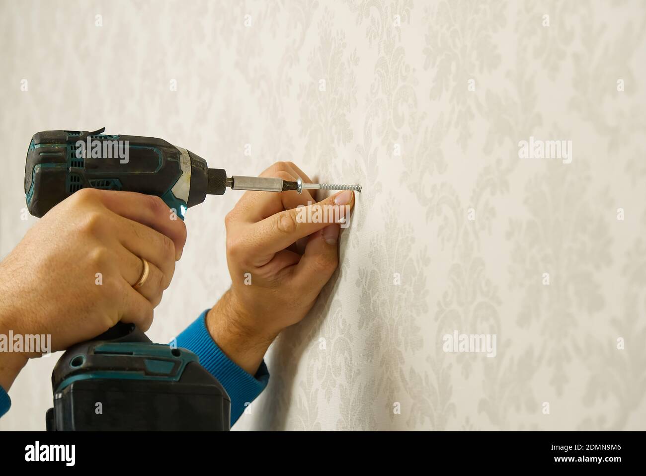 home worker drives the screw into the concrete wall using electric ...