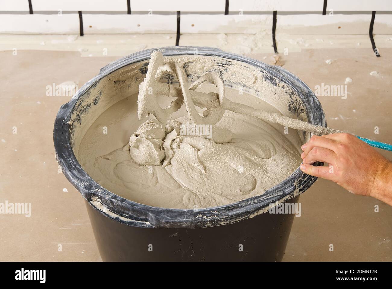the master mixes the plaster in a bucket. Flat house renovation, master ...