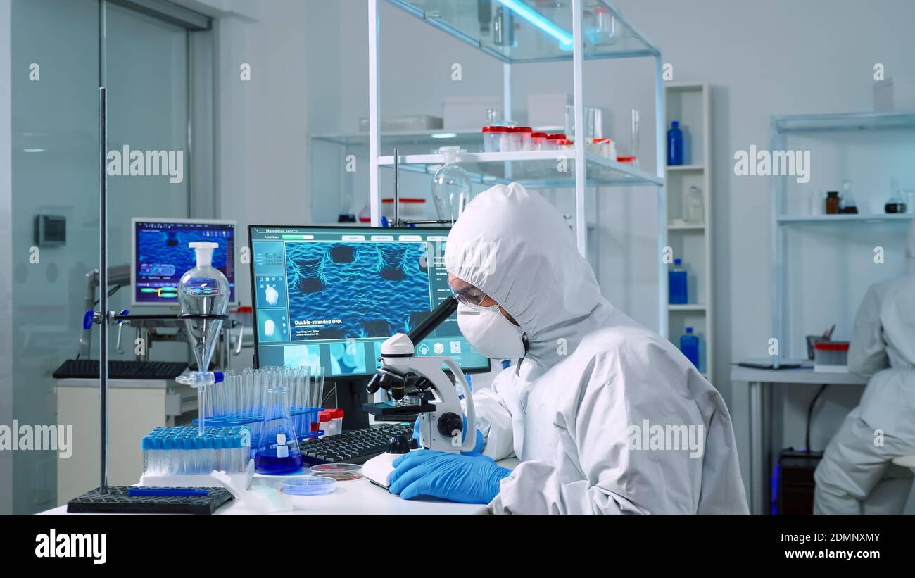Scientist in ppe suit working in laboratory using modern microscope ...