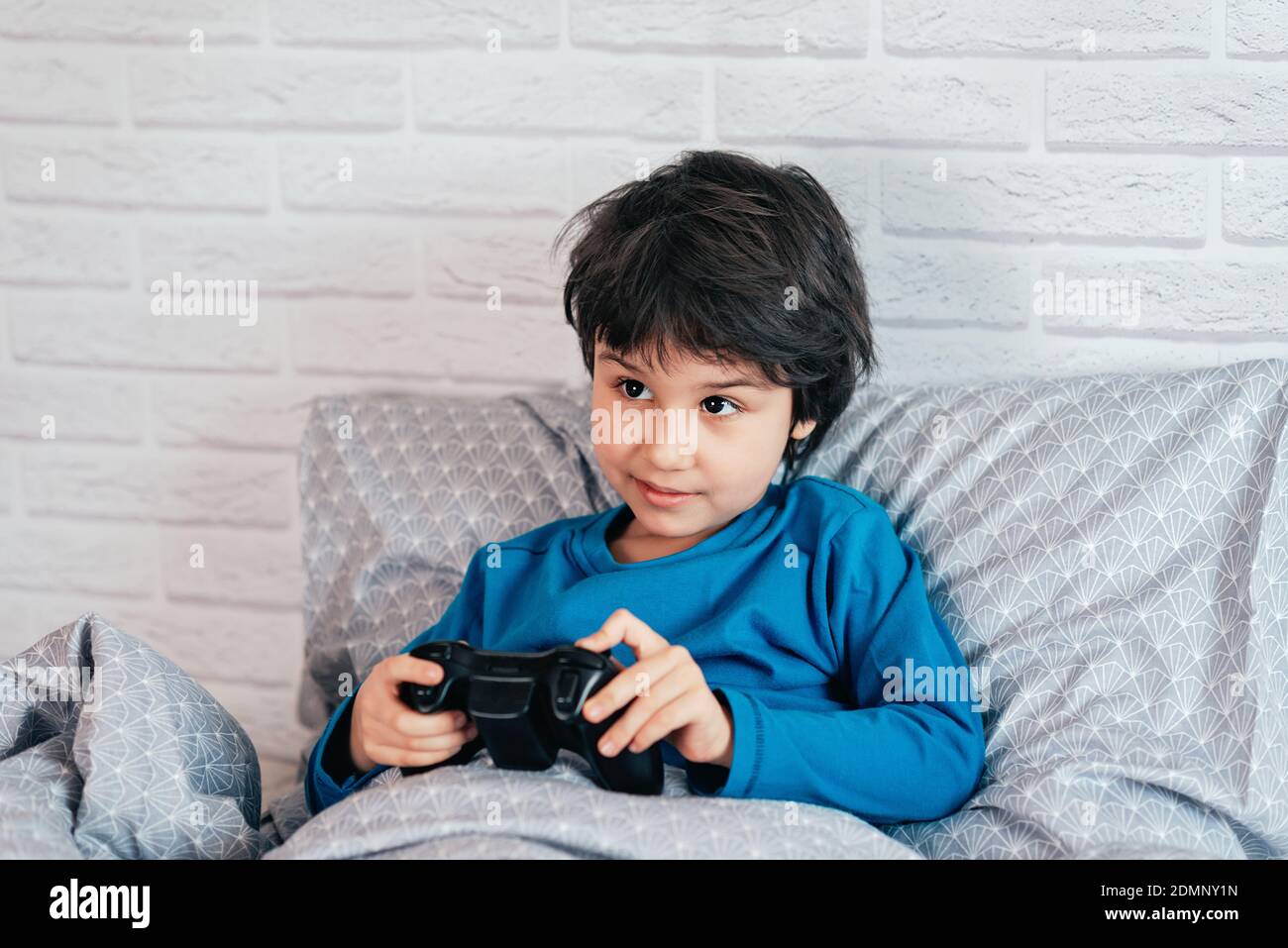 Close up of child hands playing video game at home. kid in bed wih ...