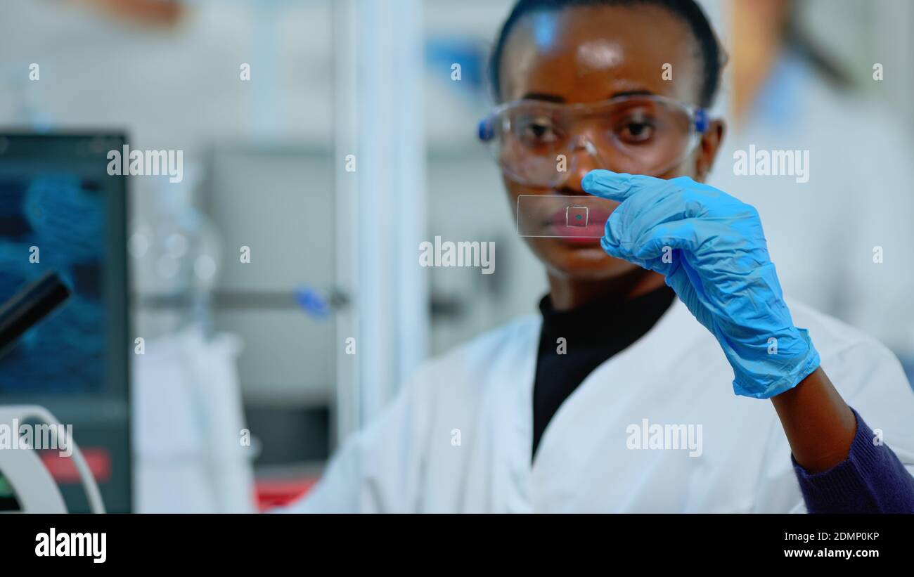 Black technician doing experiment in modern equipped lab looking at ...