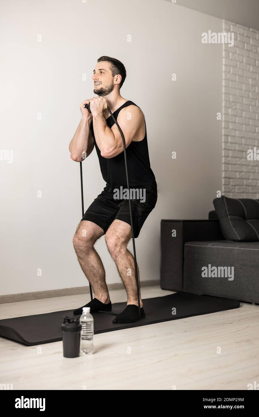 Fit man performs exercises using a resistance band. Hard workout at ...