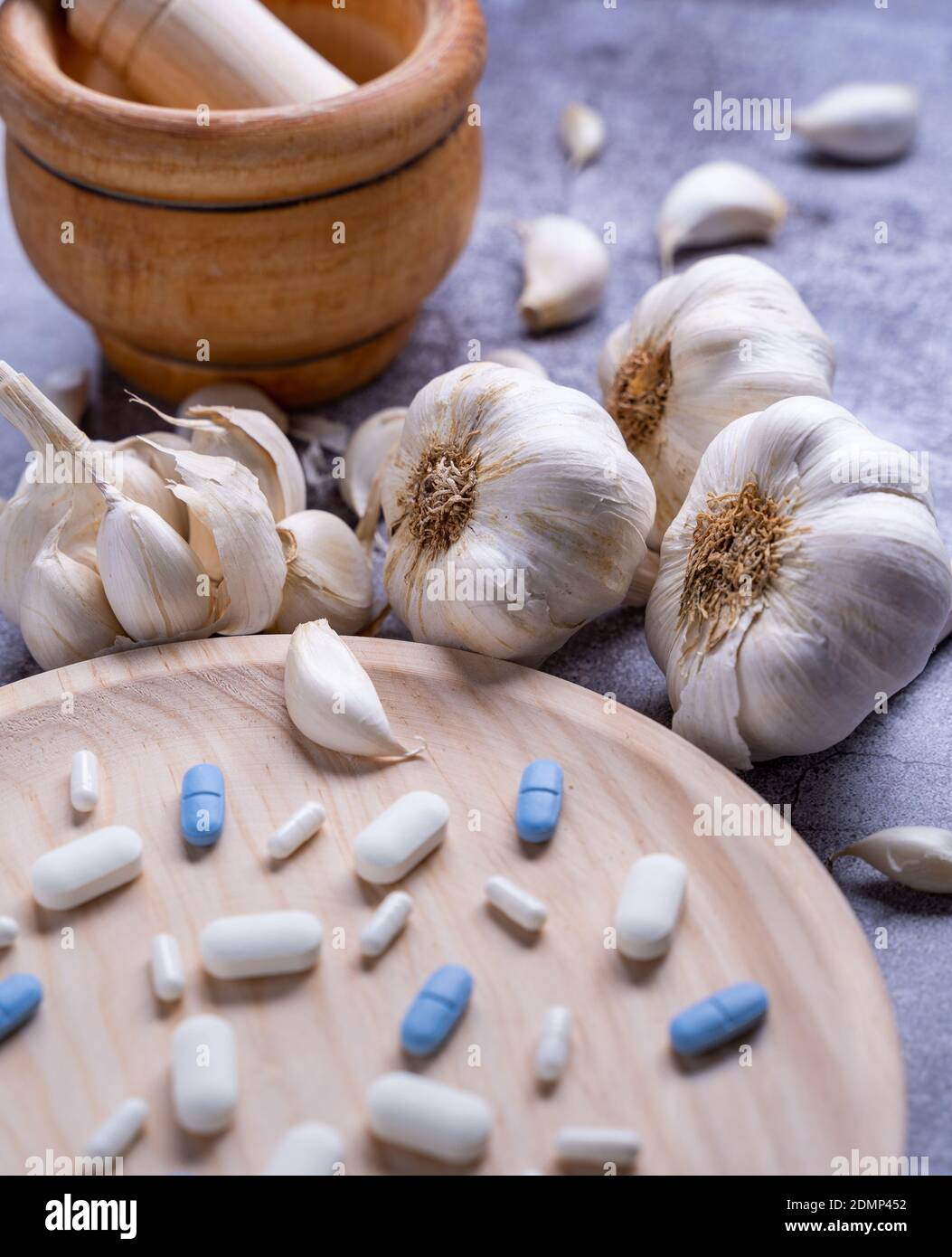 A closeup of pills on a wooden plate and garlic on the si Stock Photo ...