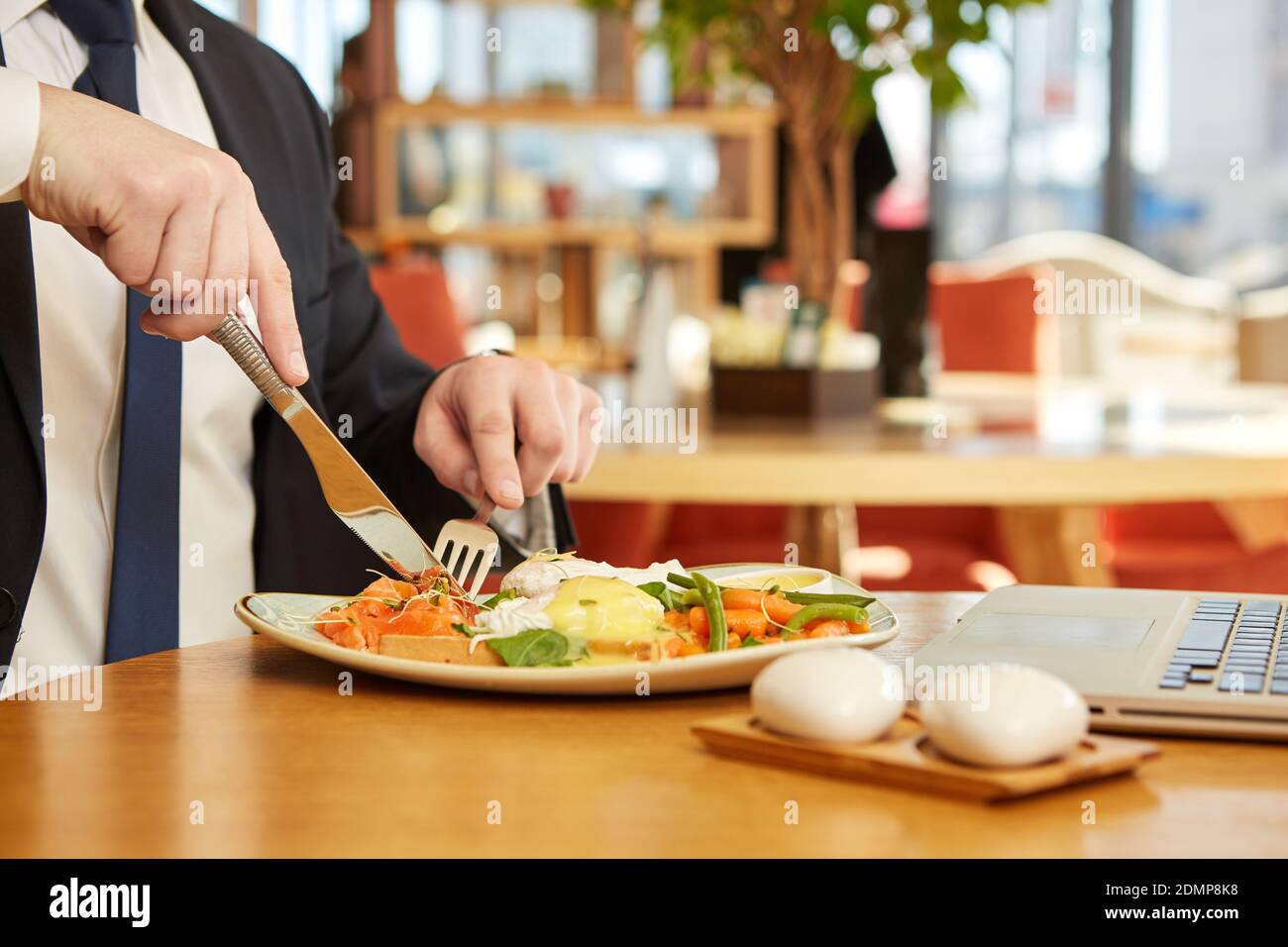 Lunch break. Cropped closeup of a businessman cutting food on his plate ...