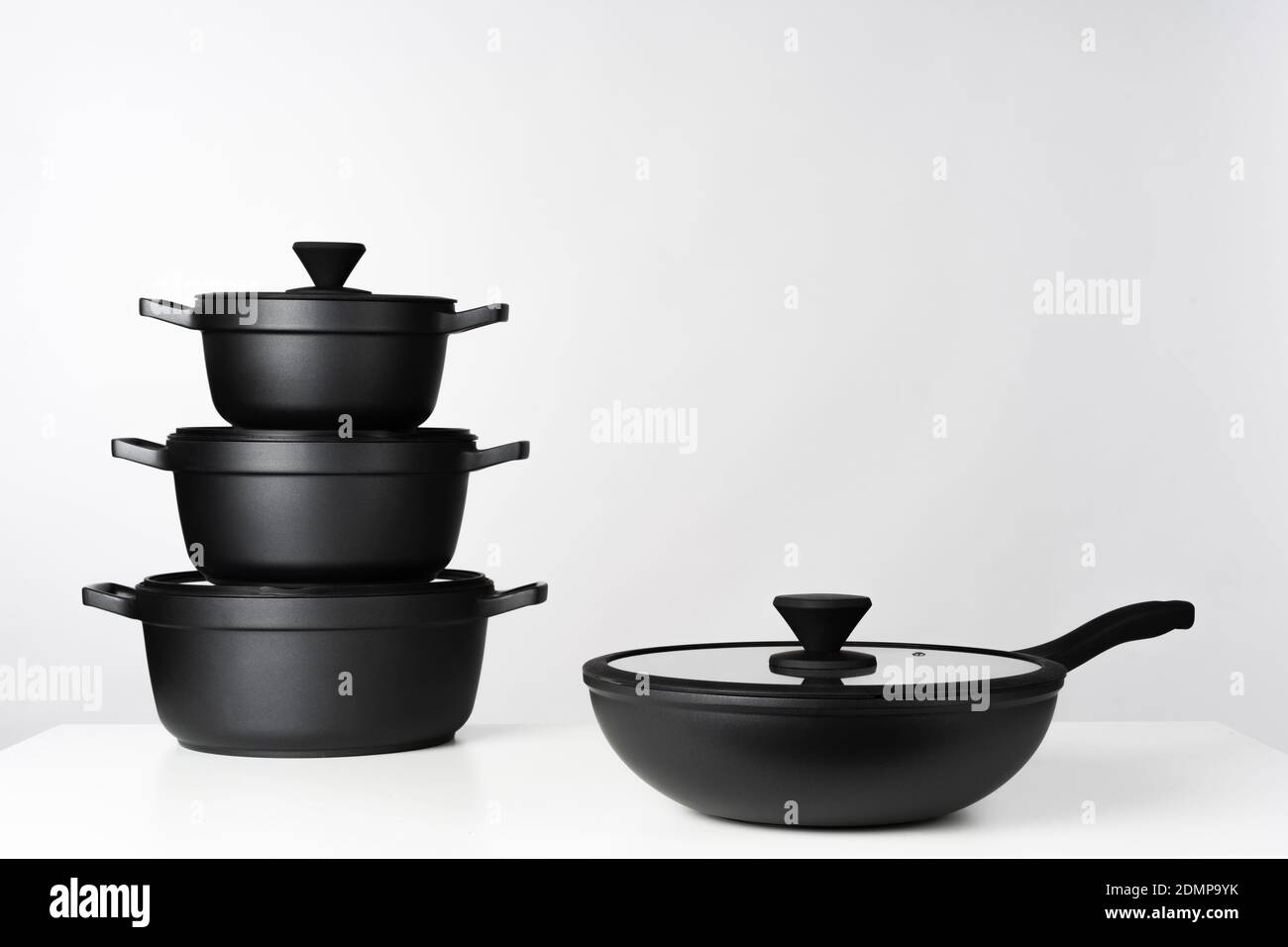 Black cooking pots on grey background front view Stock Photo - Alamy