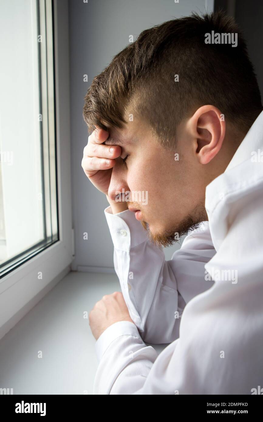 Sad Young Man by the Window in the Room Stock Photo - Alamy