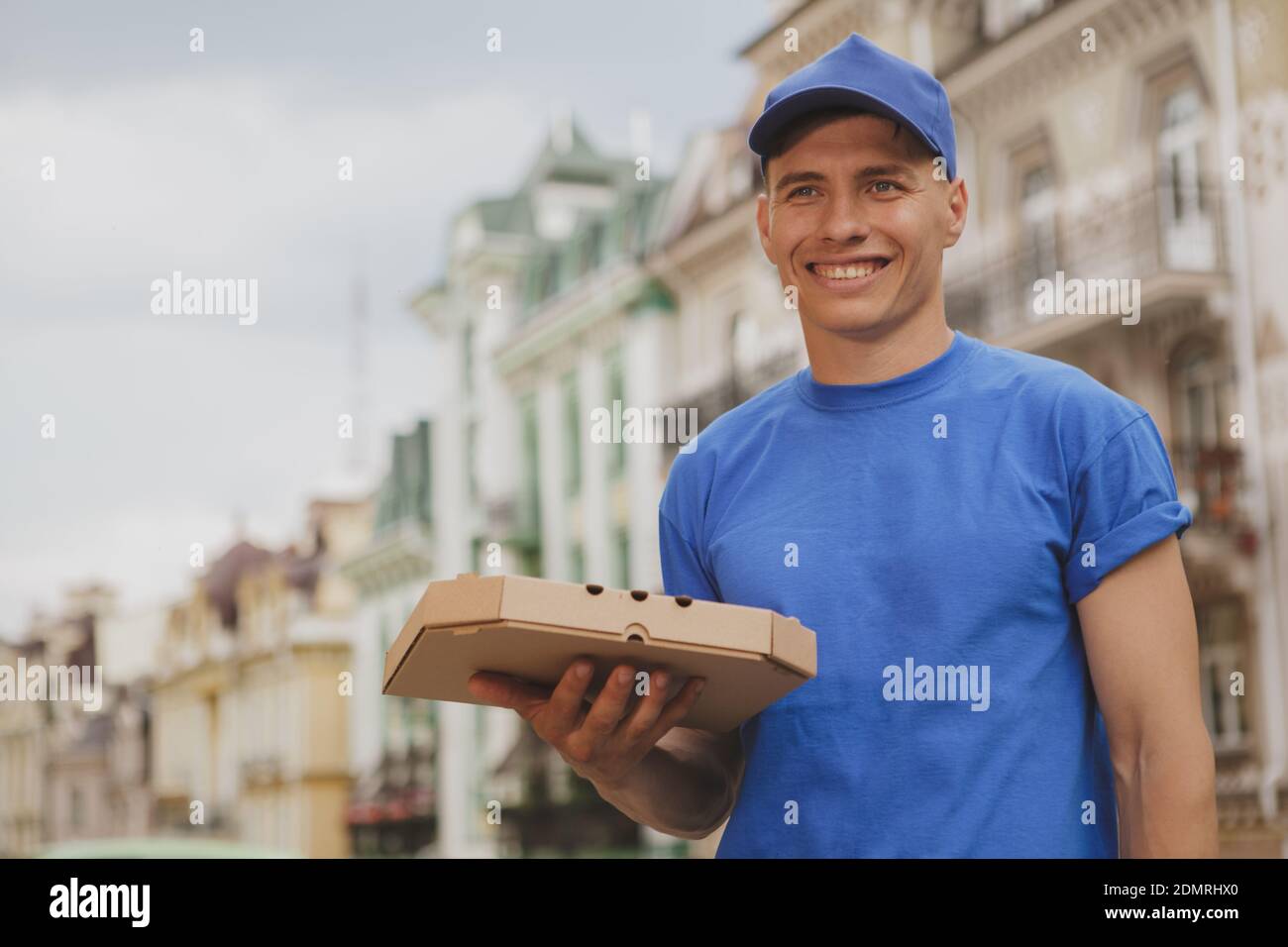 CHeerful handsome pizza delivery man working in the city, copy space ...