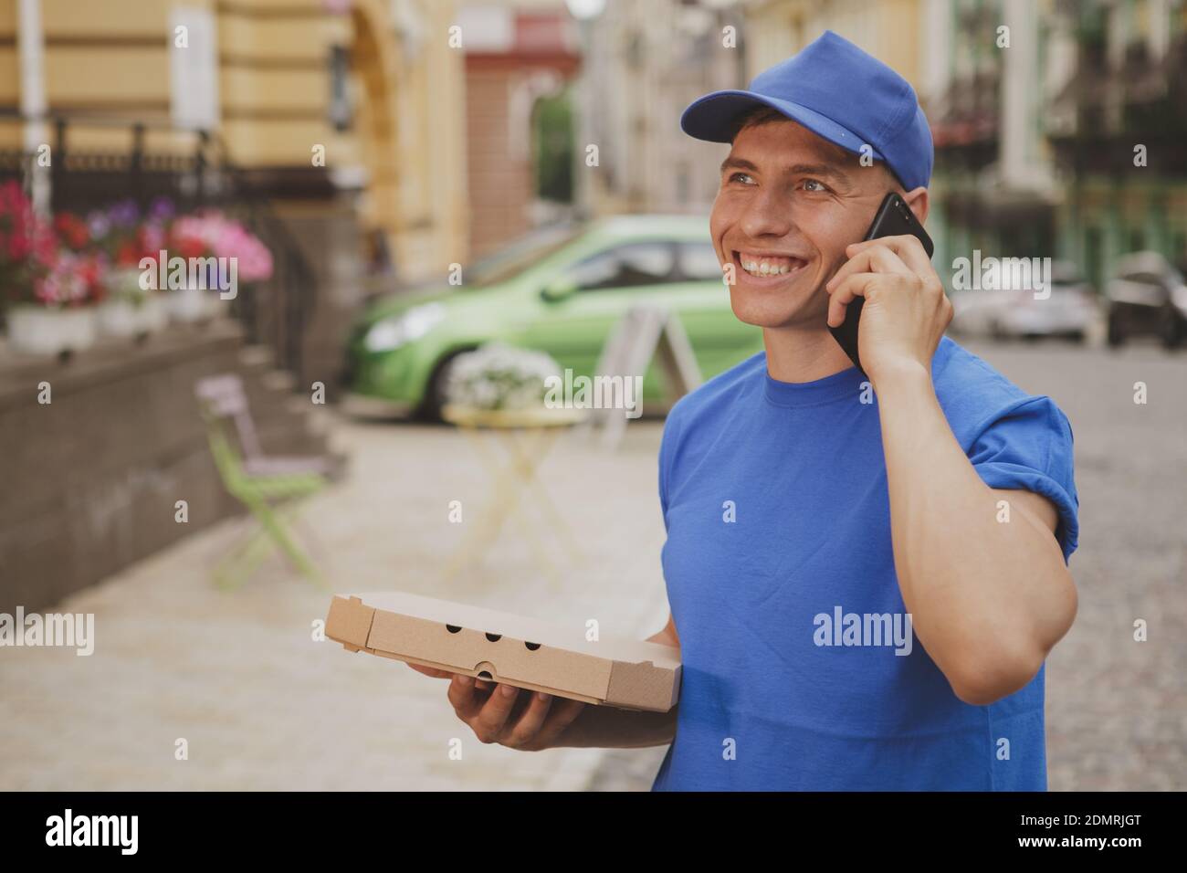 Happy handsome deliveryman holding pizza box, calling customers ...