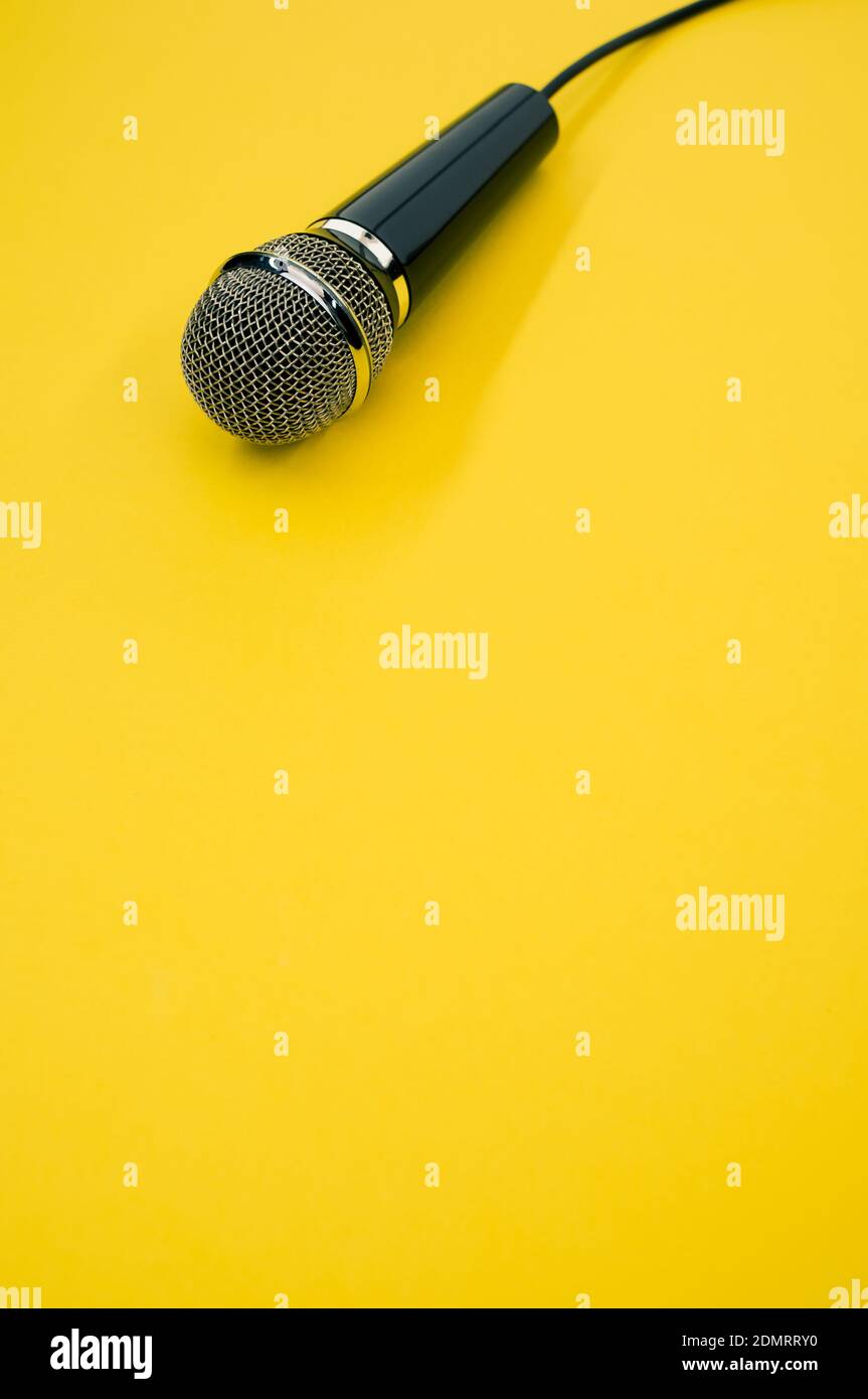 A vertical shot of a microphone on a yellow surface Stock Photo - Alamy