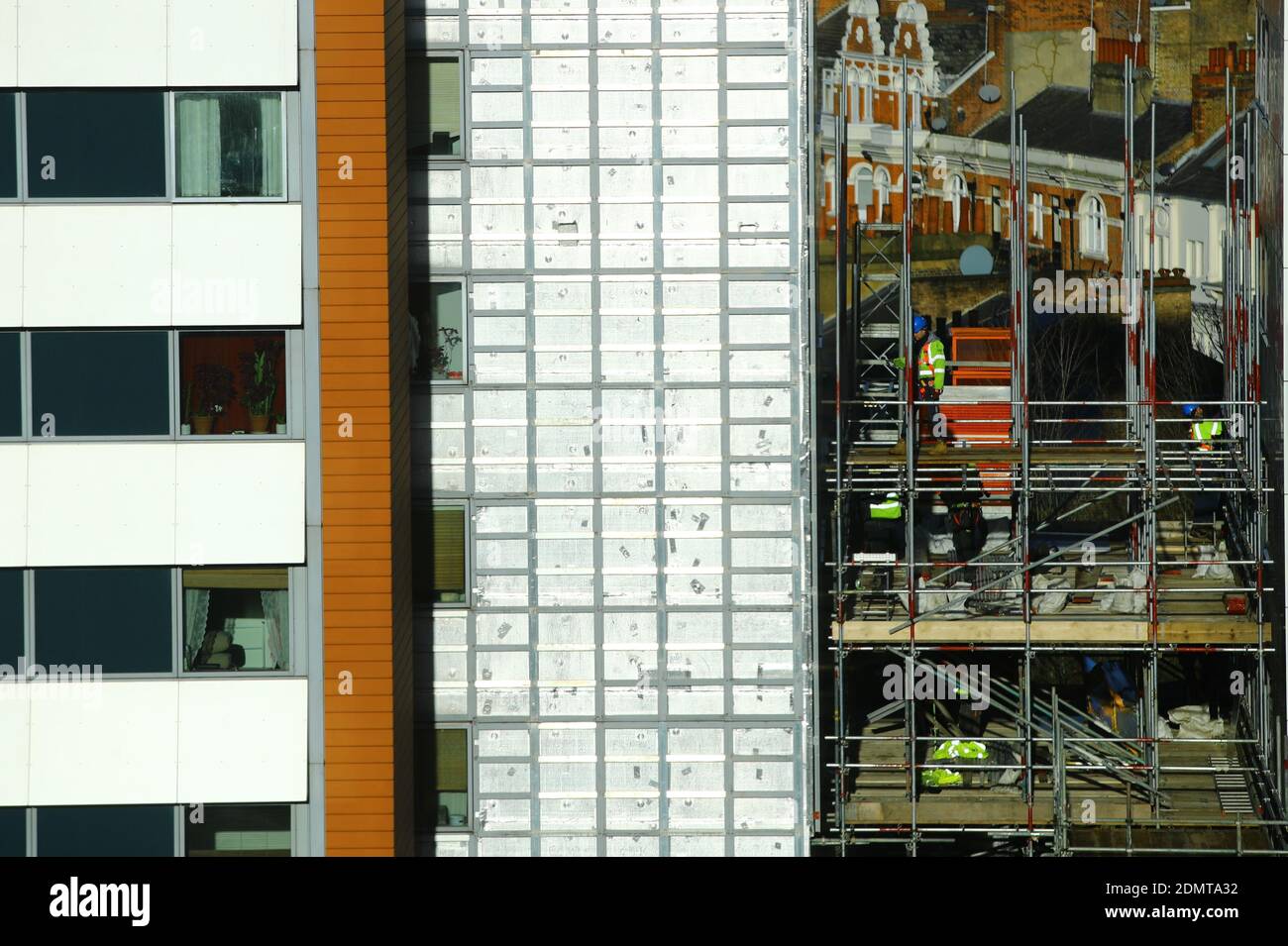 Workmen remove the cladding from the facade of a block of flats in ...