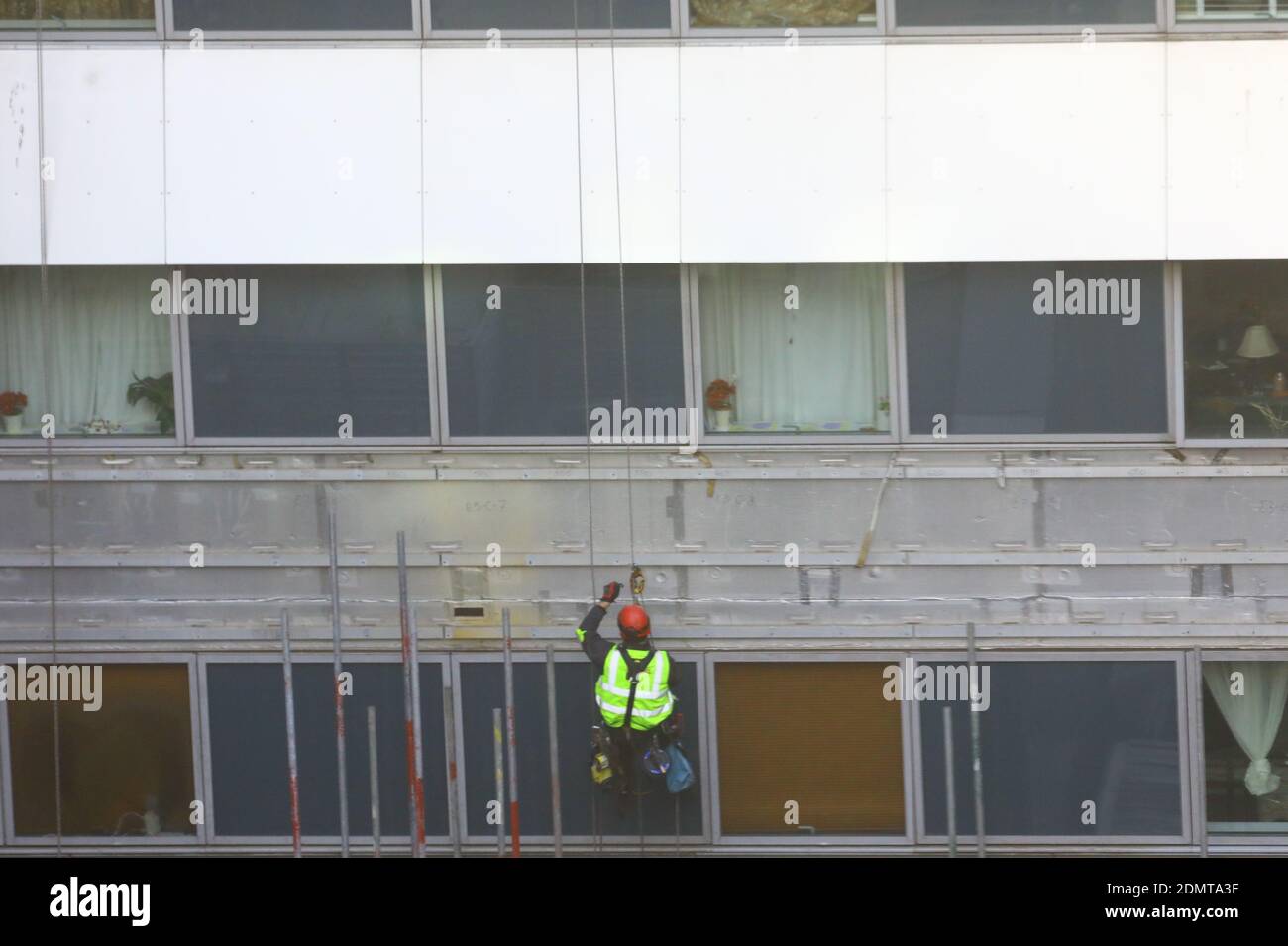 Workmen remove the cladding from the facade of a block of flats in ...