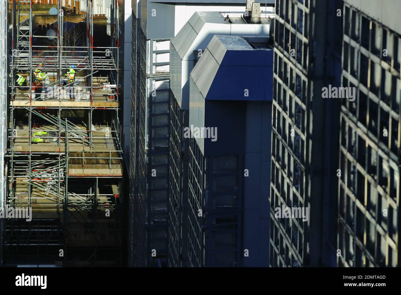Workmen remove the cladding from the facade of a block of flats in ...