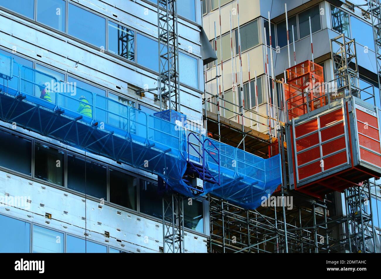 Workmen remove the cladding from the facade of a block of flats in ...