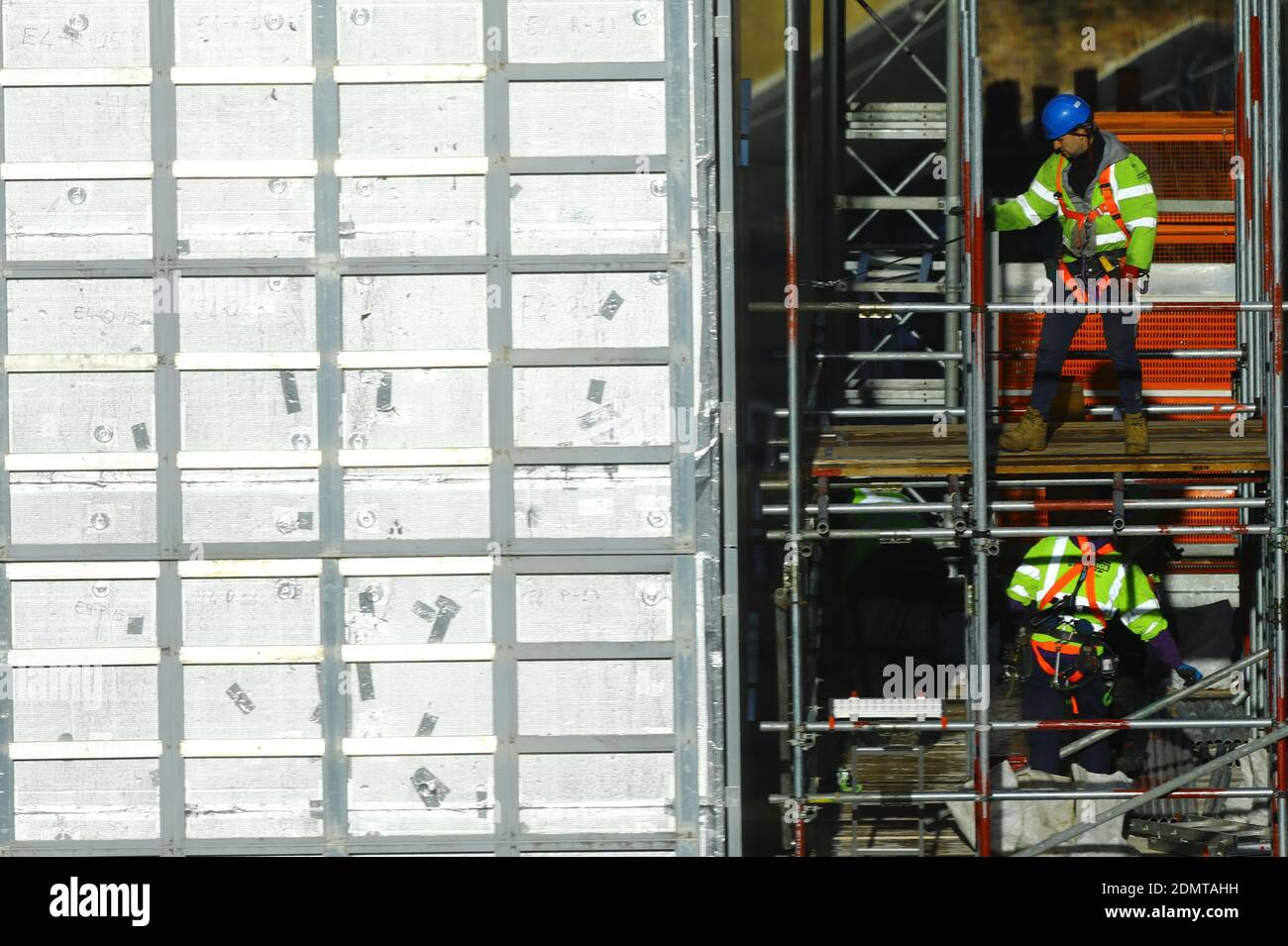 Workmen remove the cladding from the facade of a block of flats in ...