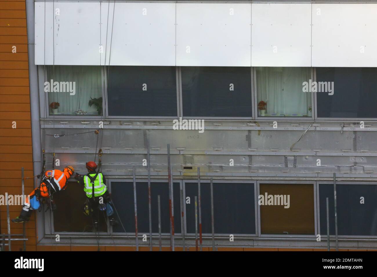 Workmen remove the cladding from the facade of a block of flats in ...