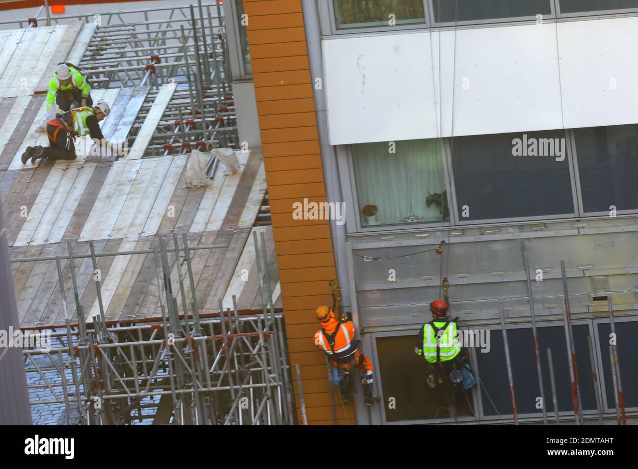 Workmen remove the cladding from the facade of a block of flats in ...