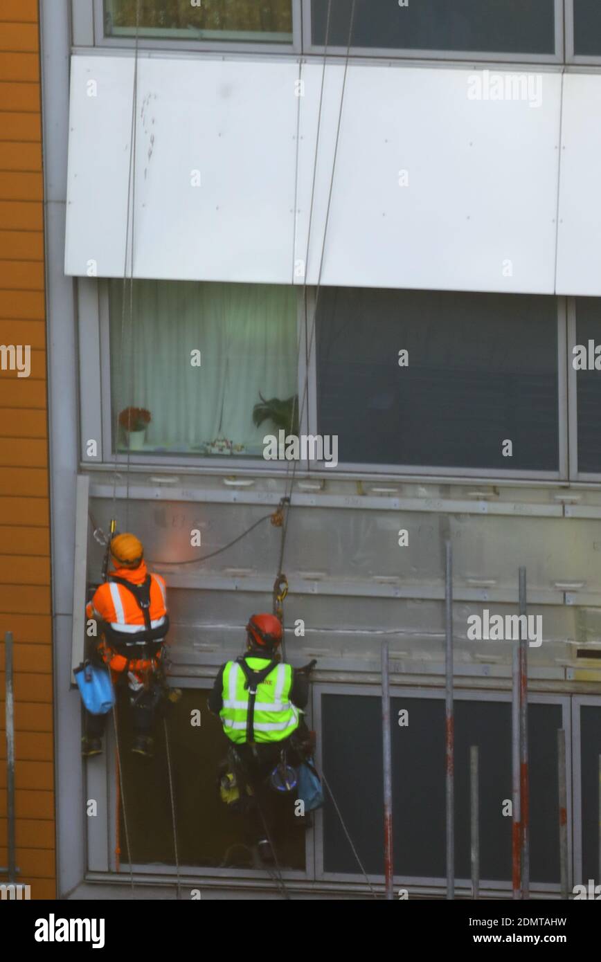 Workmen remove the cladding from the facade of a block of flats in ...