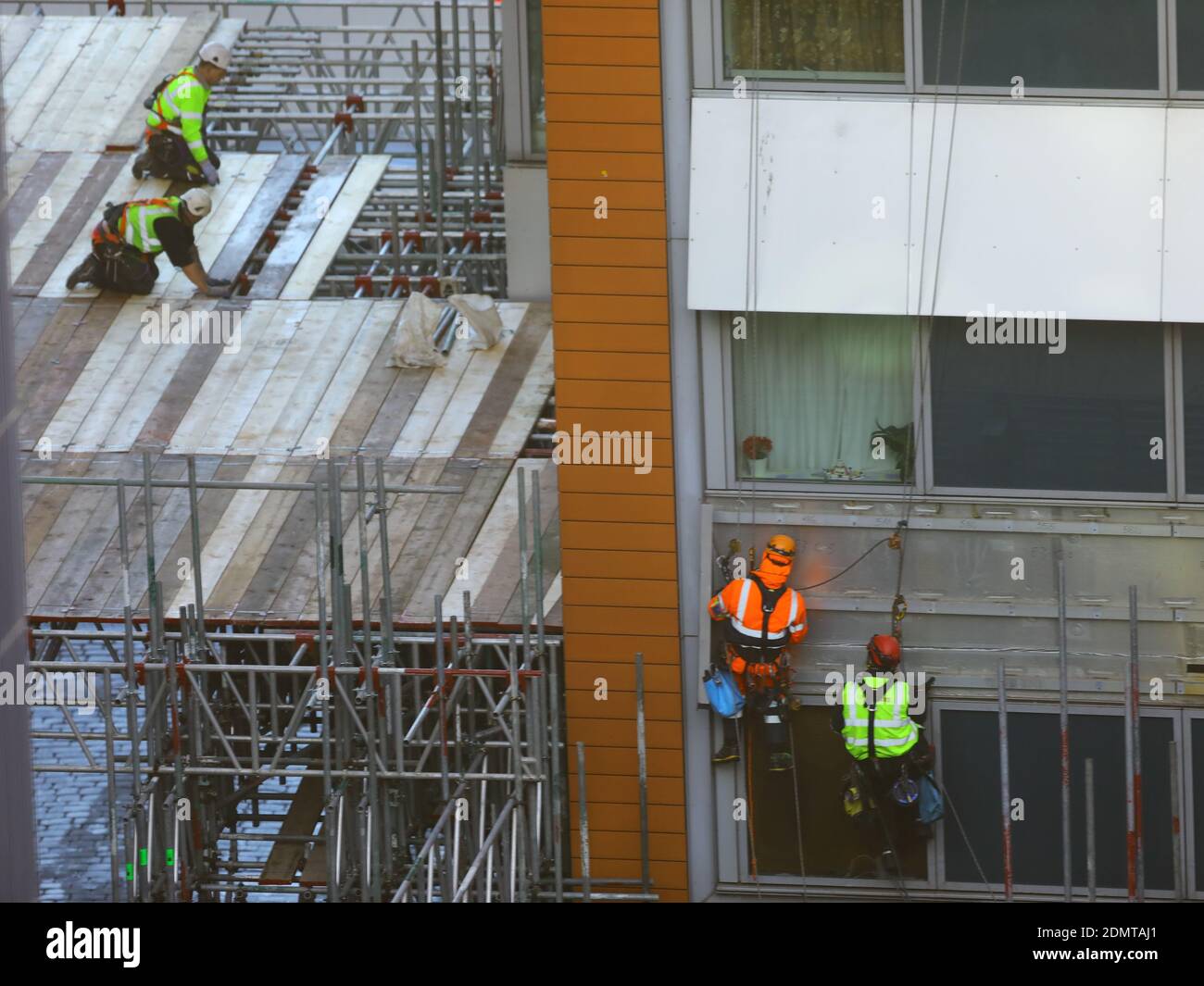 Workmen remove the cladding from the facade of a block of flats in ...