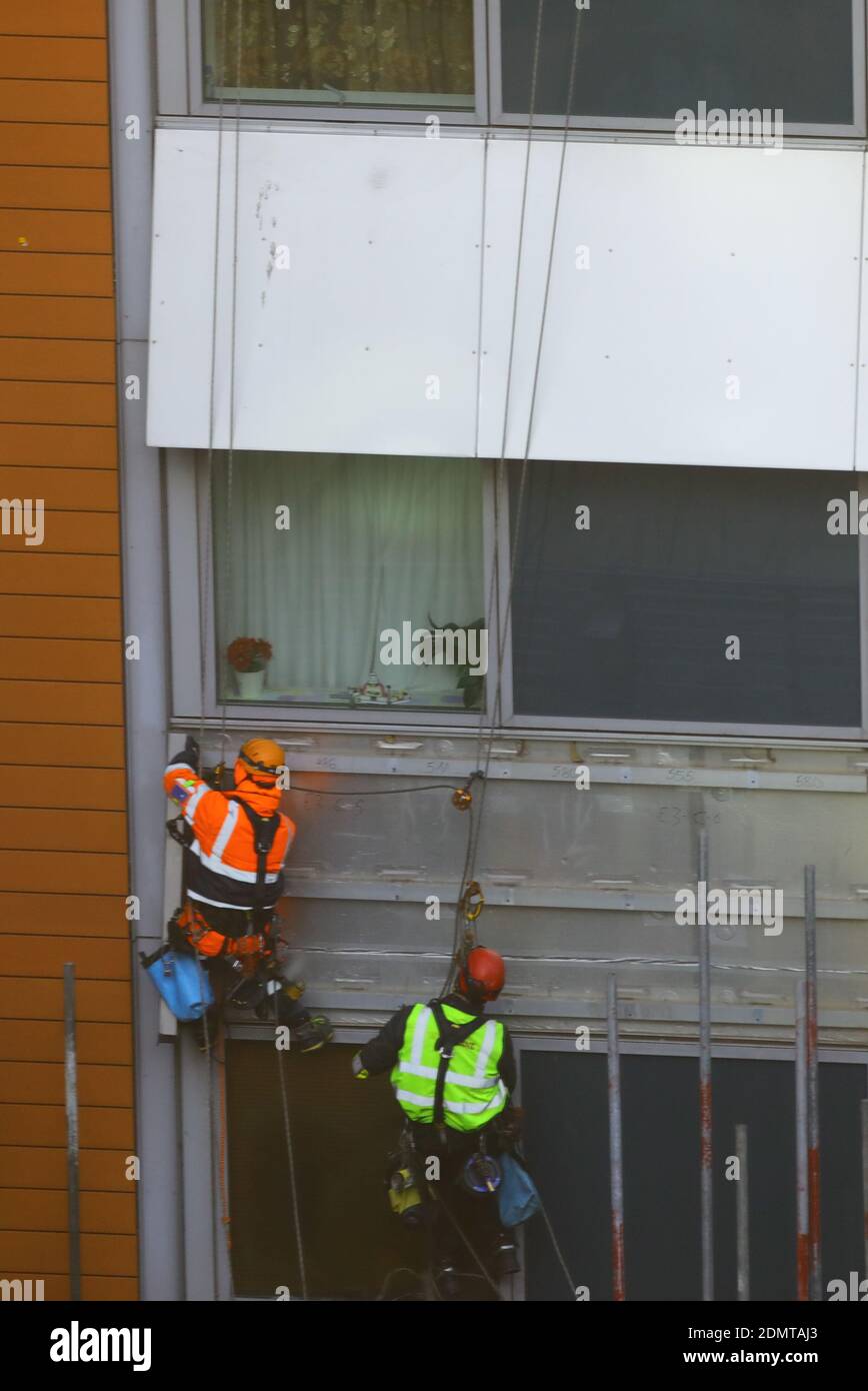 Workmen remove the cladding from the facade of a block of flats in ...