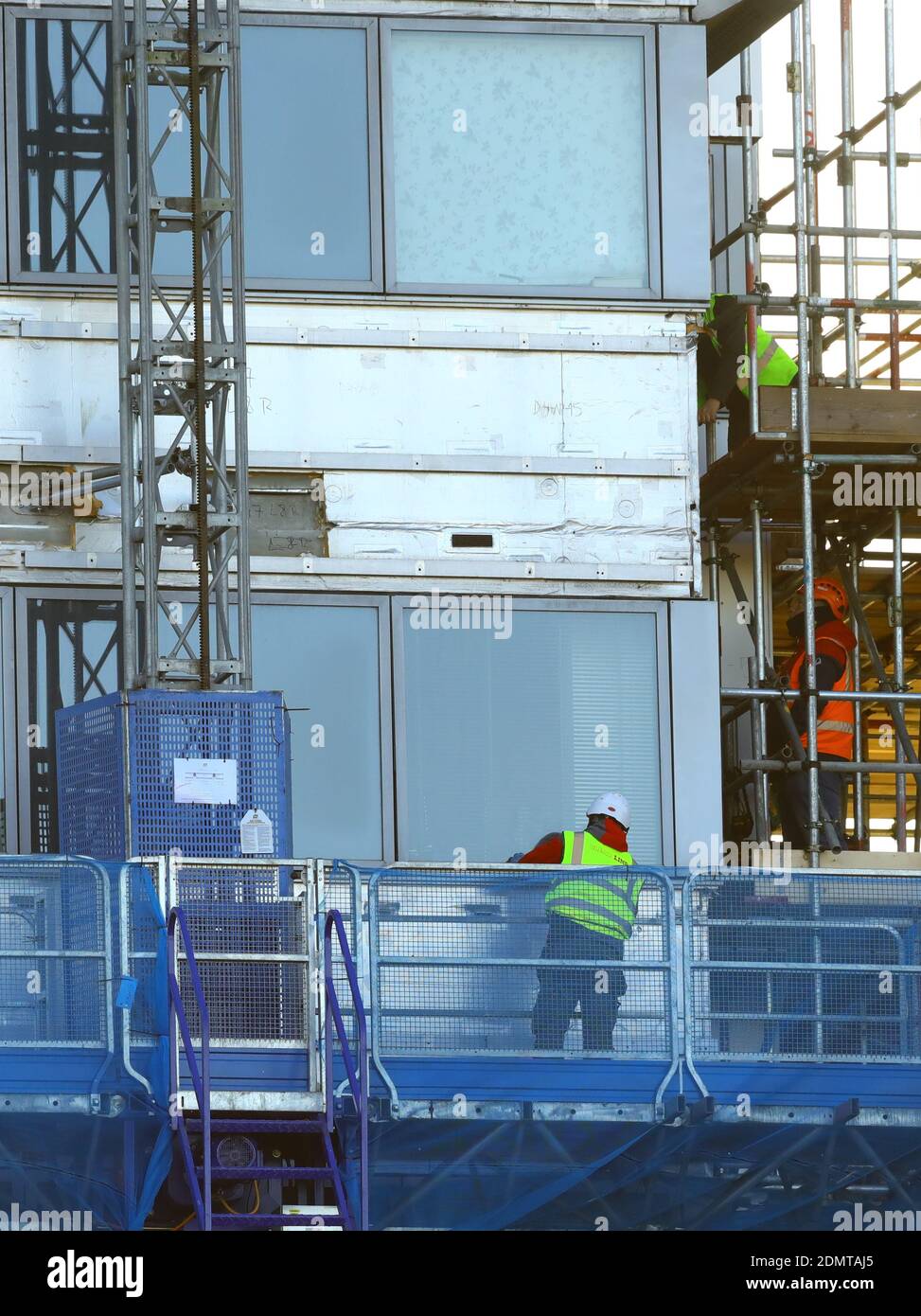 Workmen remove the cladding from the facade of a block of flats in ...