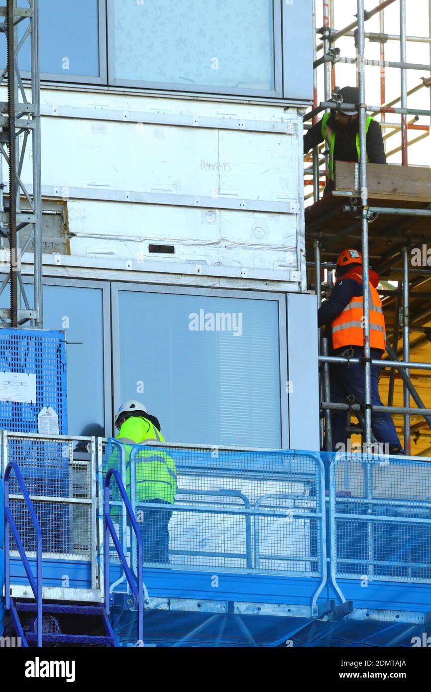 Workmen remove the cladding from the facade of a block of flats in ...
