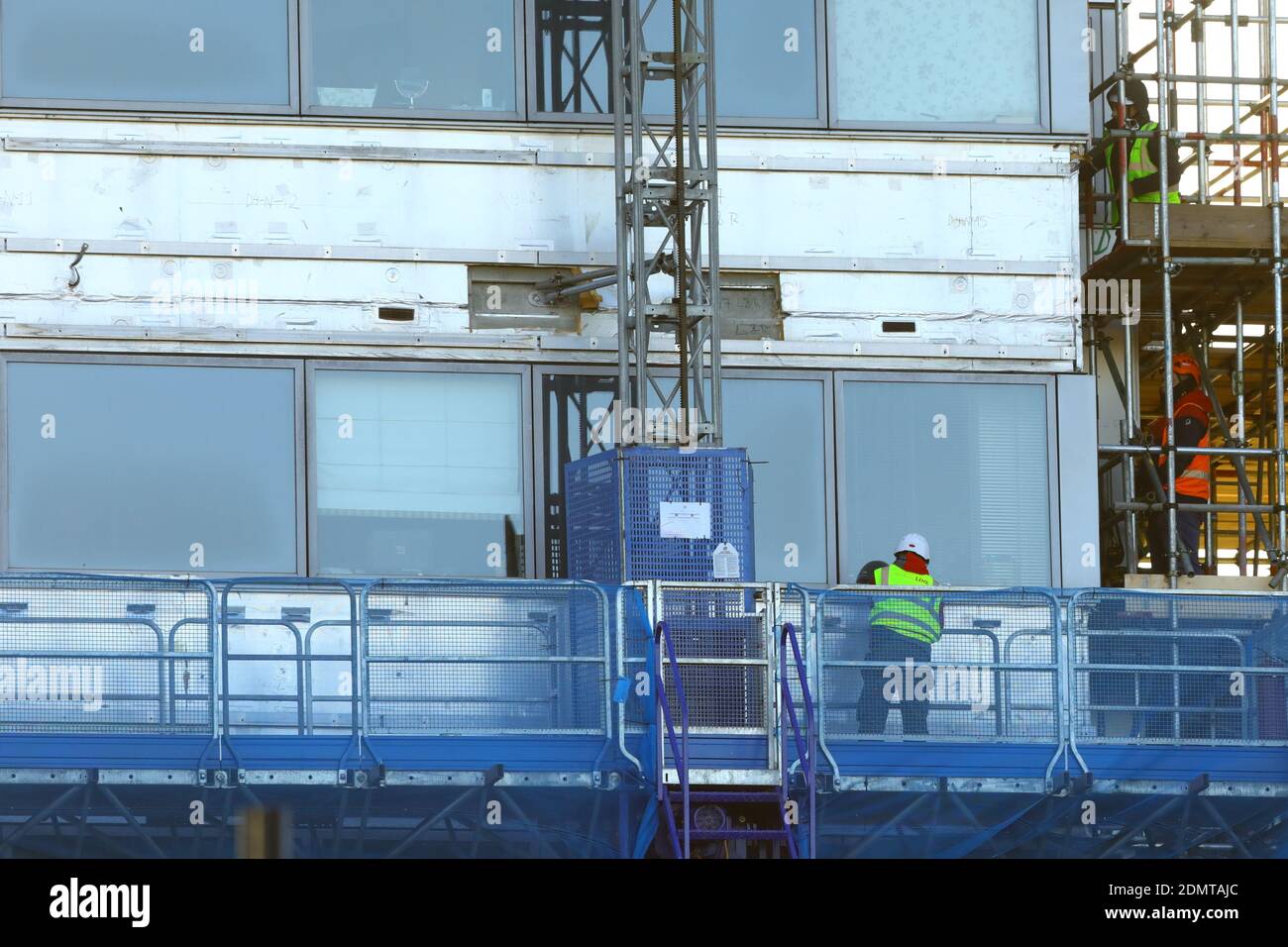Workmen remove the cladding from the facade of a block of flats in ...