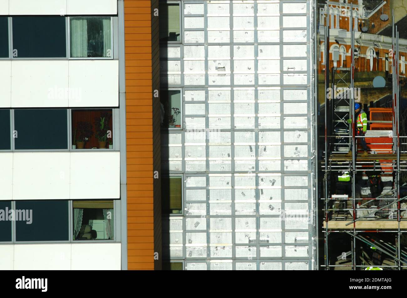 Workmen remove the cladding from the facade of a block of flats in ...