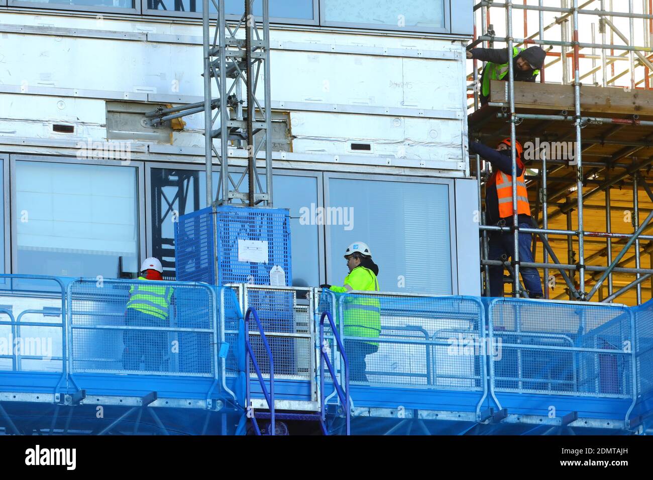Workmen remove the cladding from the facade of a block of flats in ...