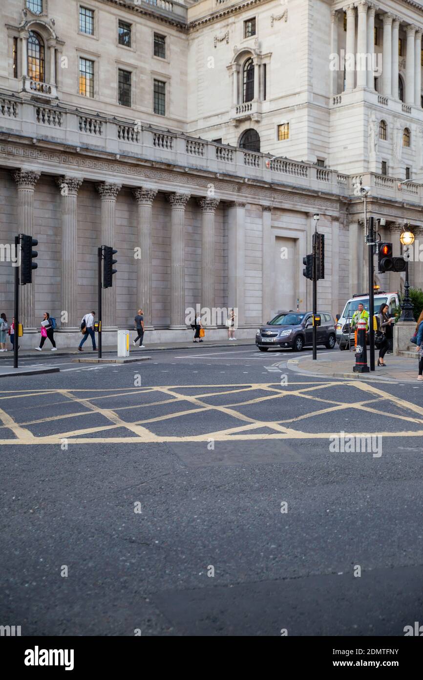 British street with pedestrians walking outside a big classical ...