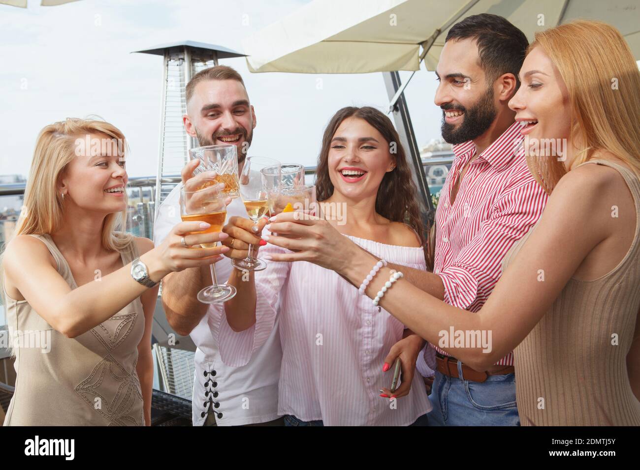 Happy young people screaming joyfully, toasting with their glasses ...