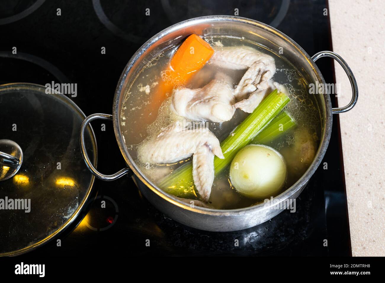 top view of chicken wings broth is cooked in steel stewpot on stove at ...