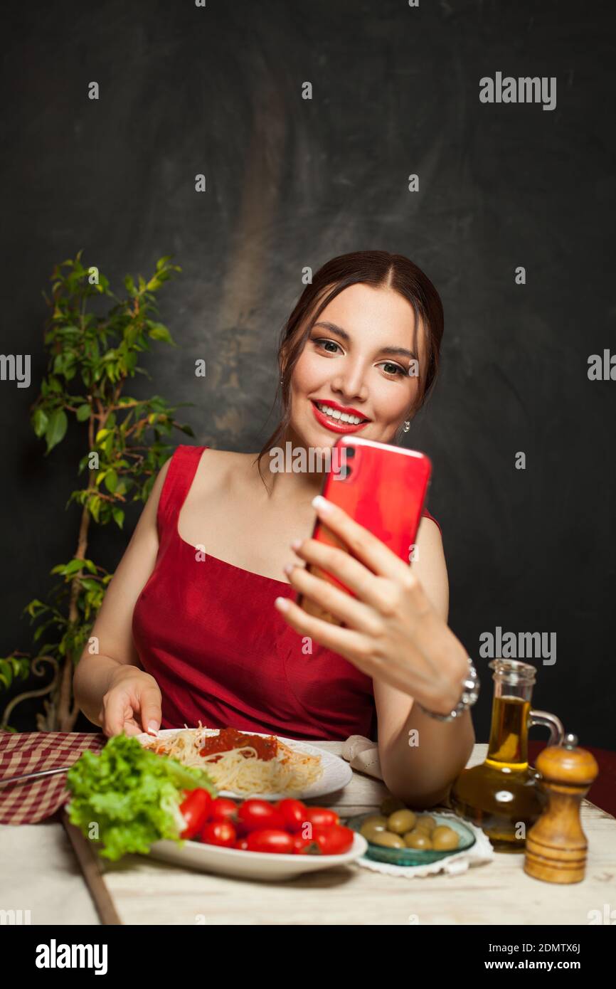 Happy woman taking a selfie and eating italian pasta in restaurant ...