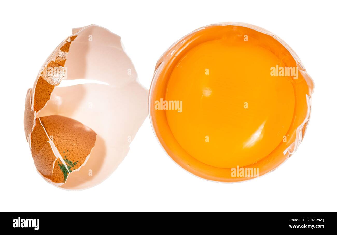 top view of separated egg yolk in shell and crushed eggshell isolated ...
