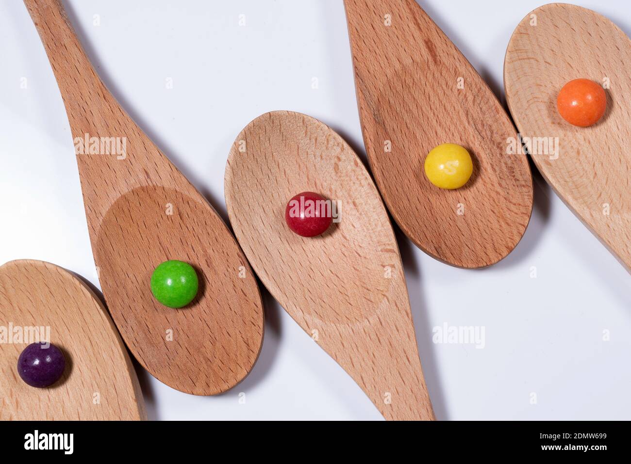 Five wood spoons on white background with colorful candy Stock Photo ...