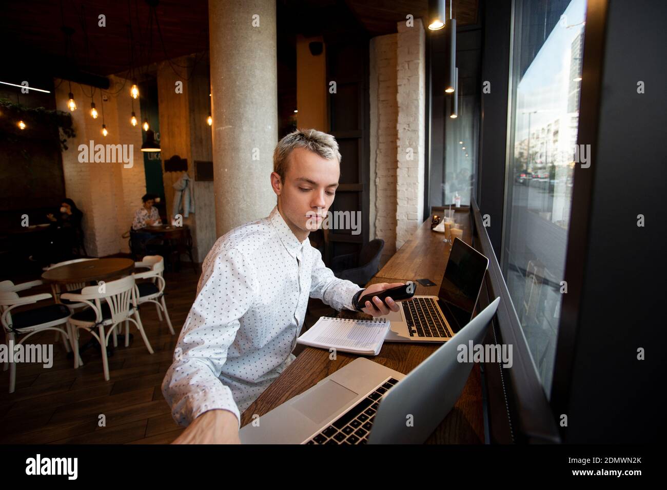 Freelance programmer sits near the window in a coffee shop and works ...
