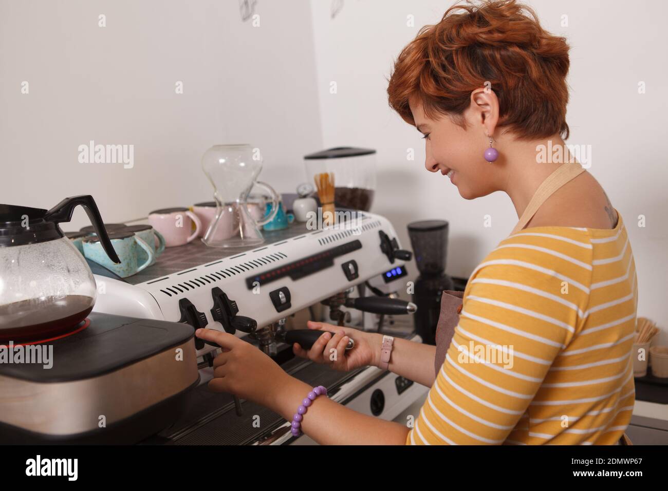 Rear view shot of a female barista making coffee using coffee machine ...