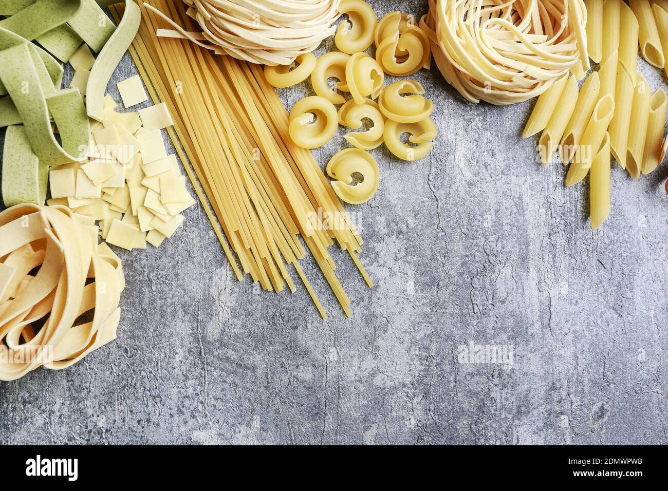 Mixed types and shapes of italian pasta on grey stone background. Copy ...