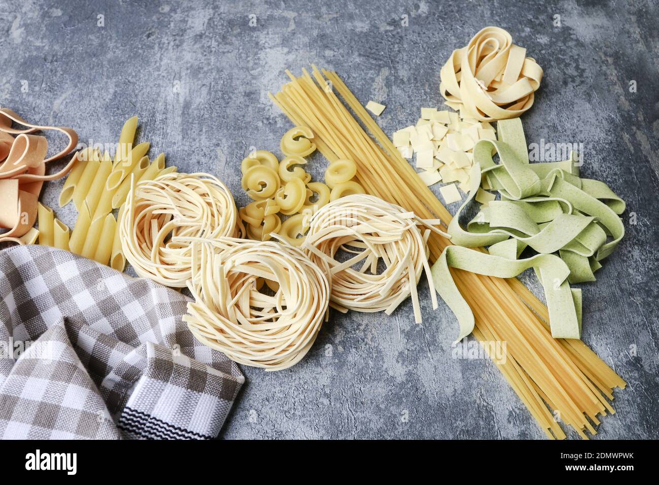 Mixed types and shapes of italian pasta on grey stone background. Copy ...