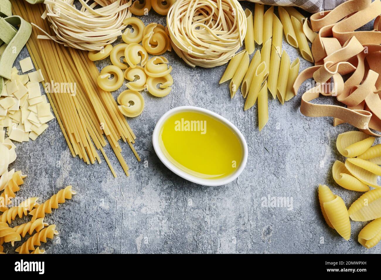Mixed types and shapes of italian pasta on grey stone background. Copy ...