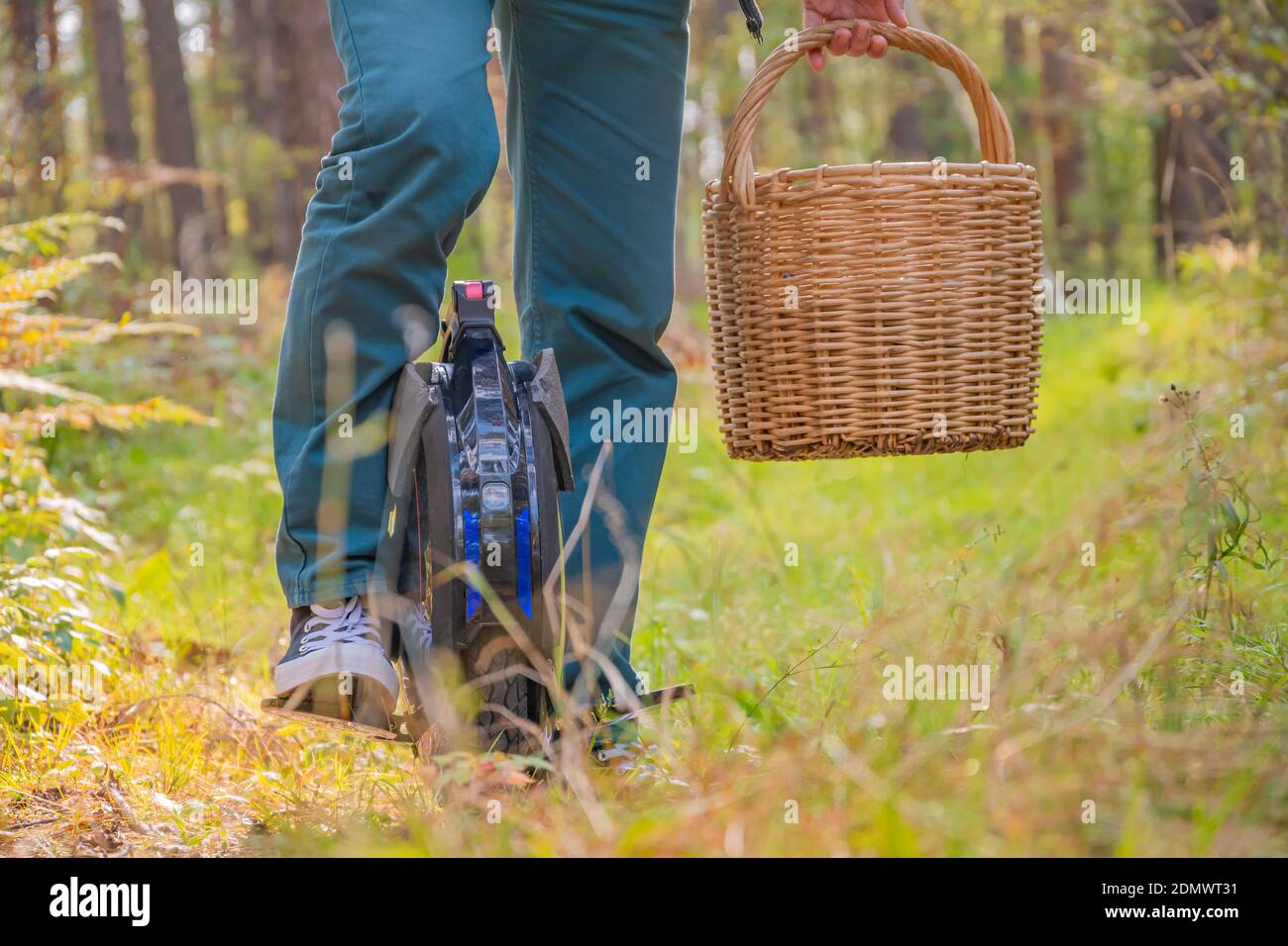 Front view of men's legs on an electric unicycle in the forest. A man ...