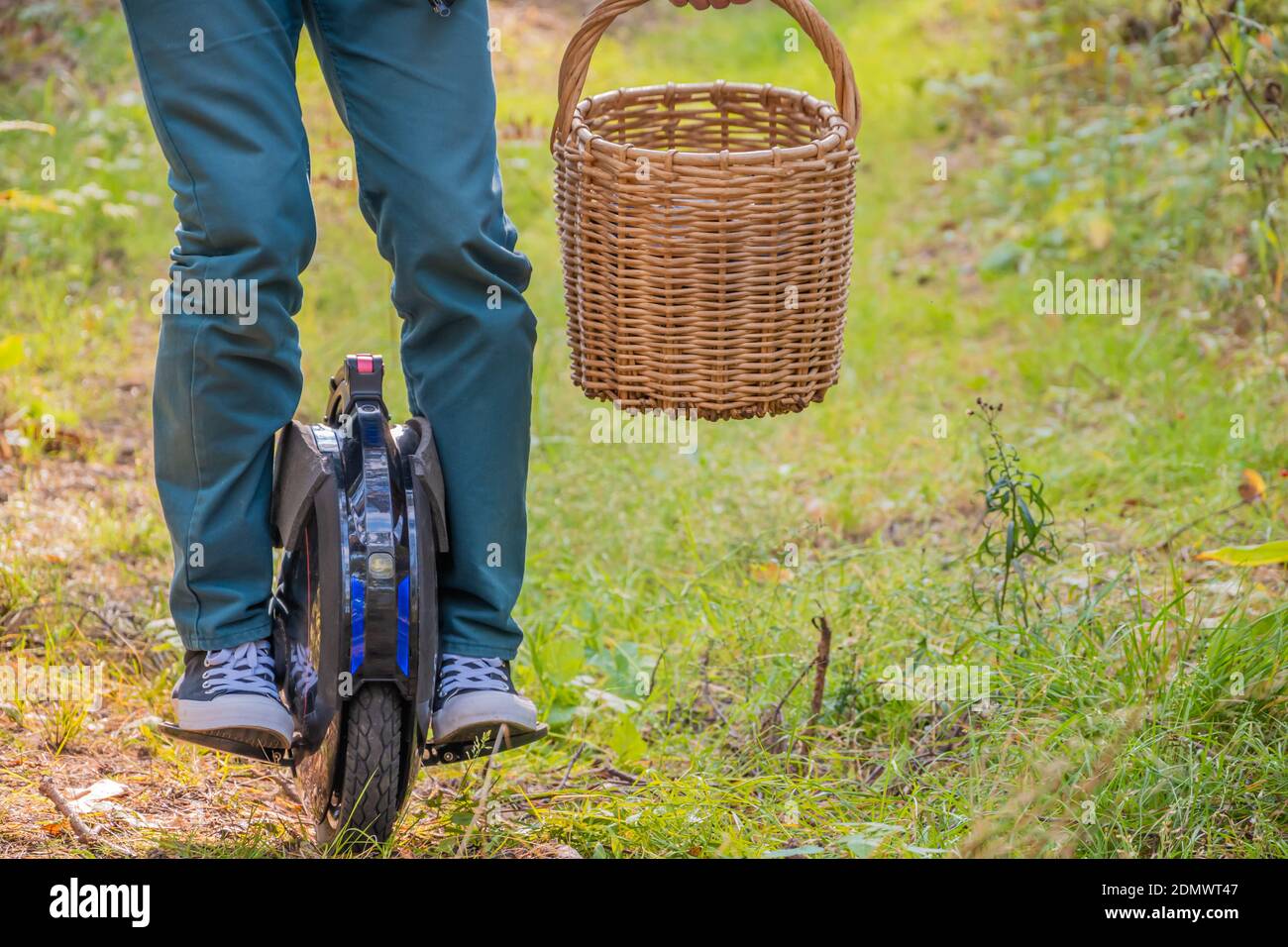 Front view of men's legs on an electric unicycle in the forest. A man ...