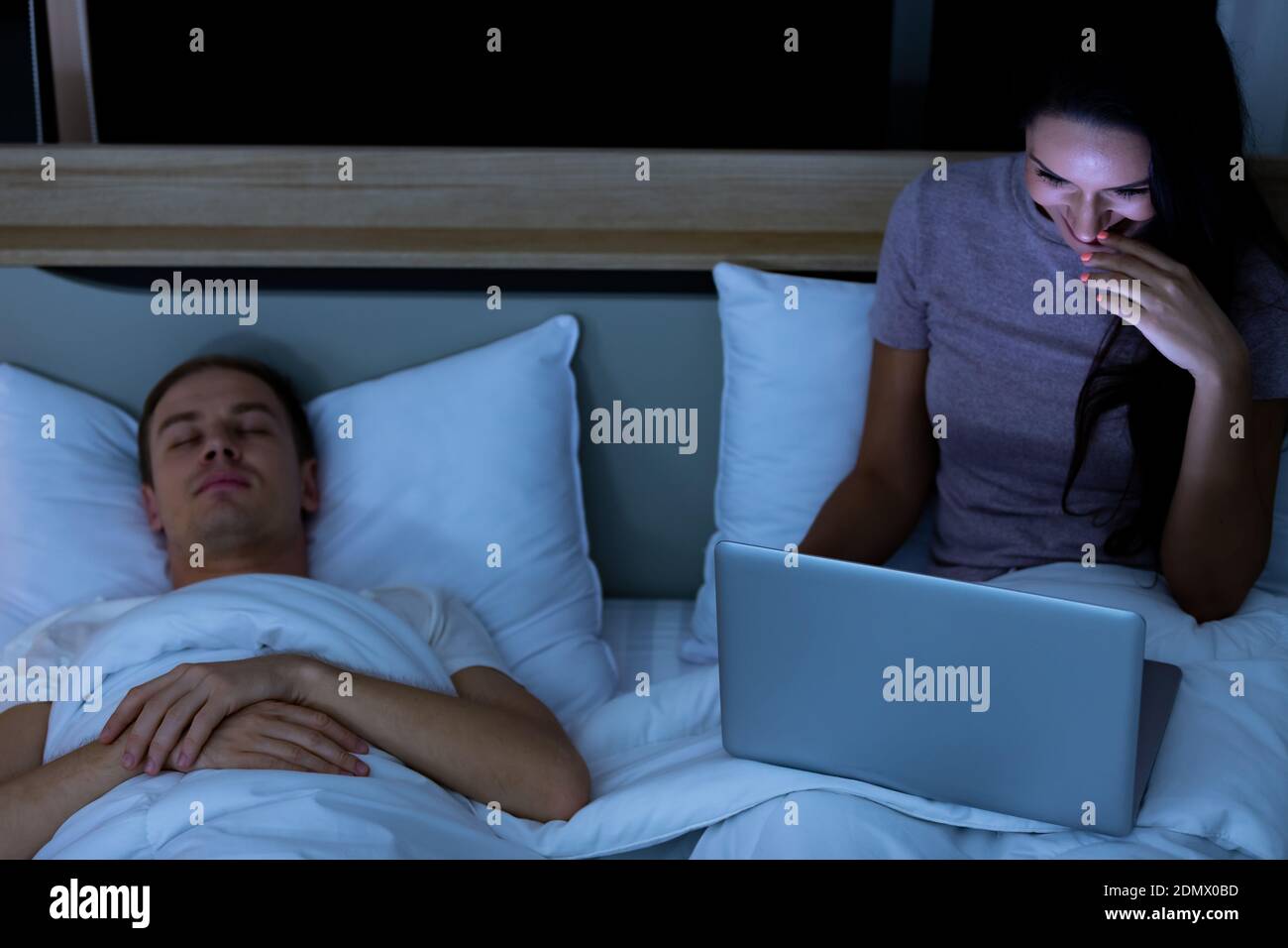 Woman sitting on bed in the night and using laptop computer while ...
