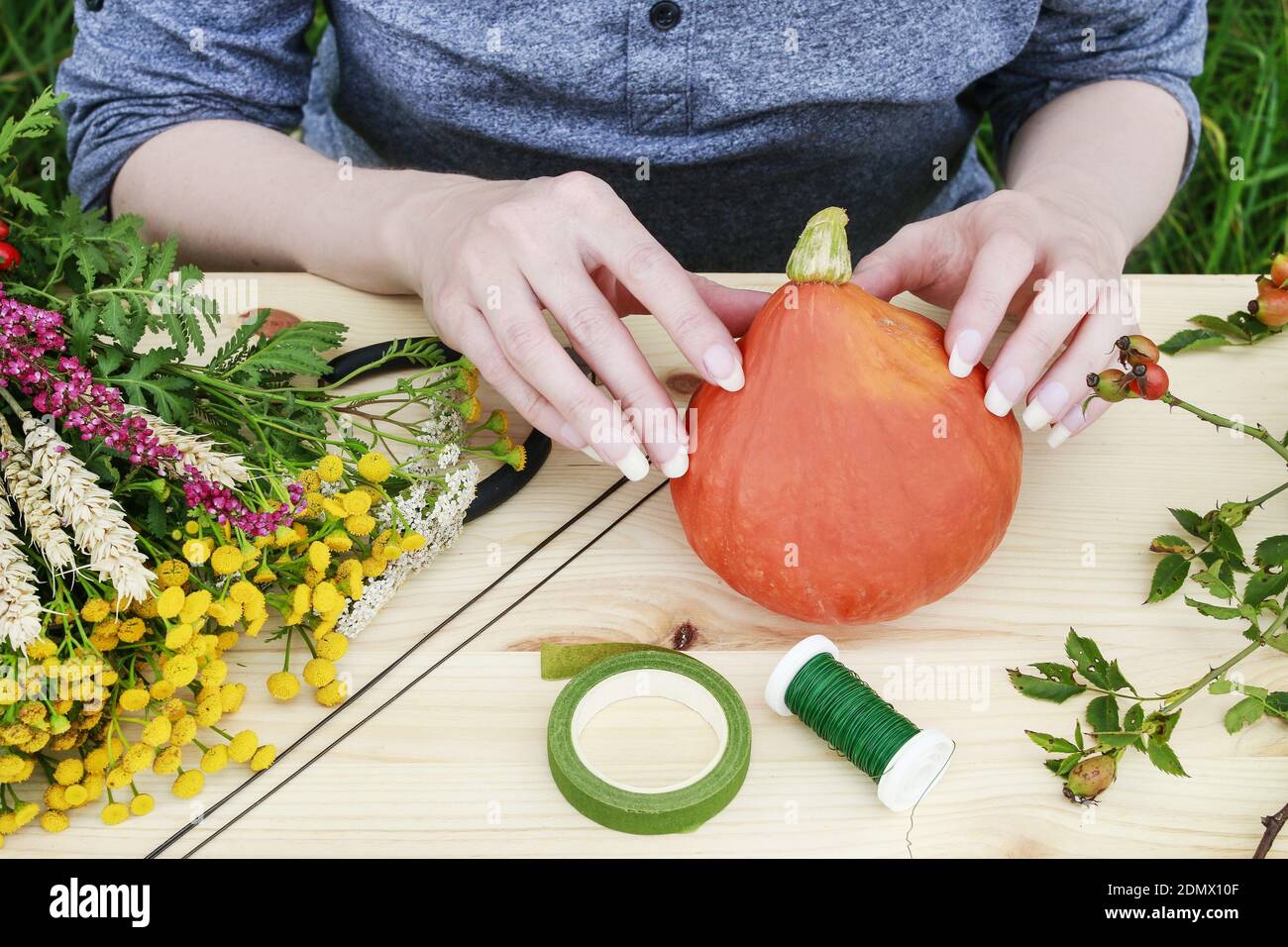 Florist at work: Woman decorating pumpkin with wild plants. Autumn home ...