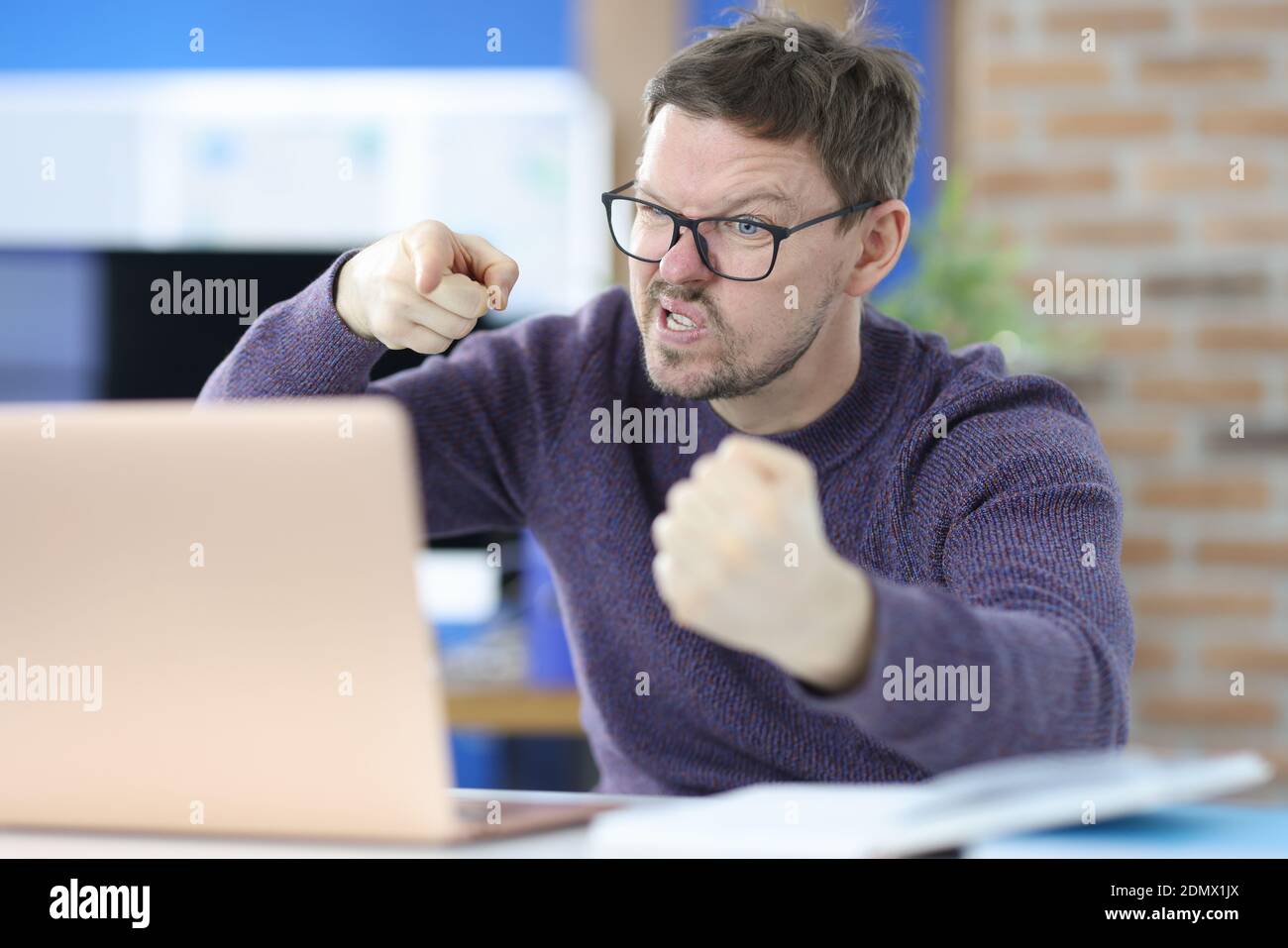 Angry man sits at work table in front of laptop Stock Photo - Alamy