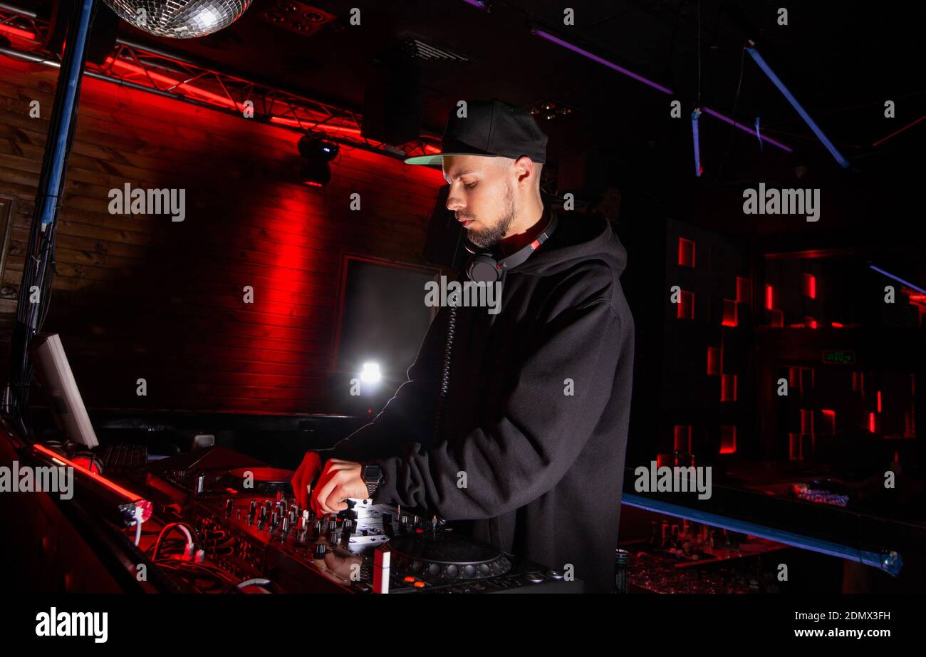 Confident DJ mixes music in cool night club. High tech concept. Bright ...