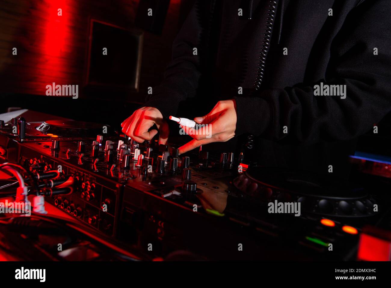Male DJ's hand turn tumblers and hold electronic cigarette. Close up ...