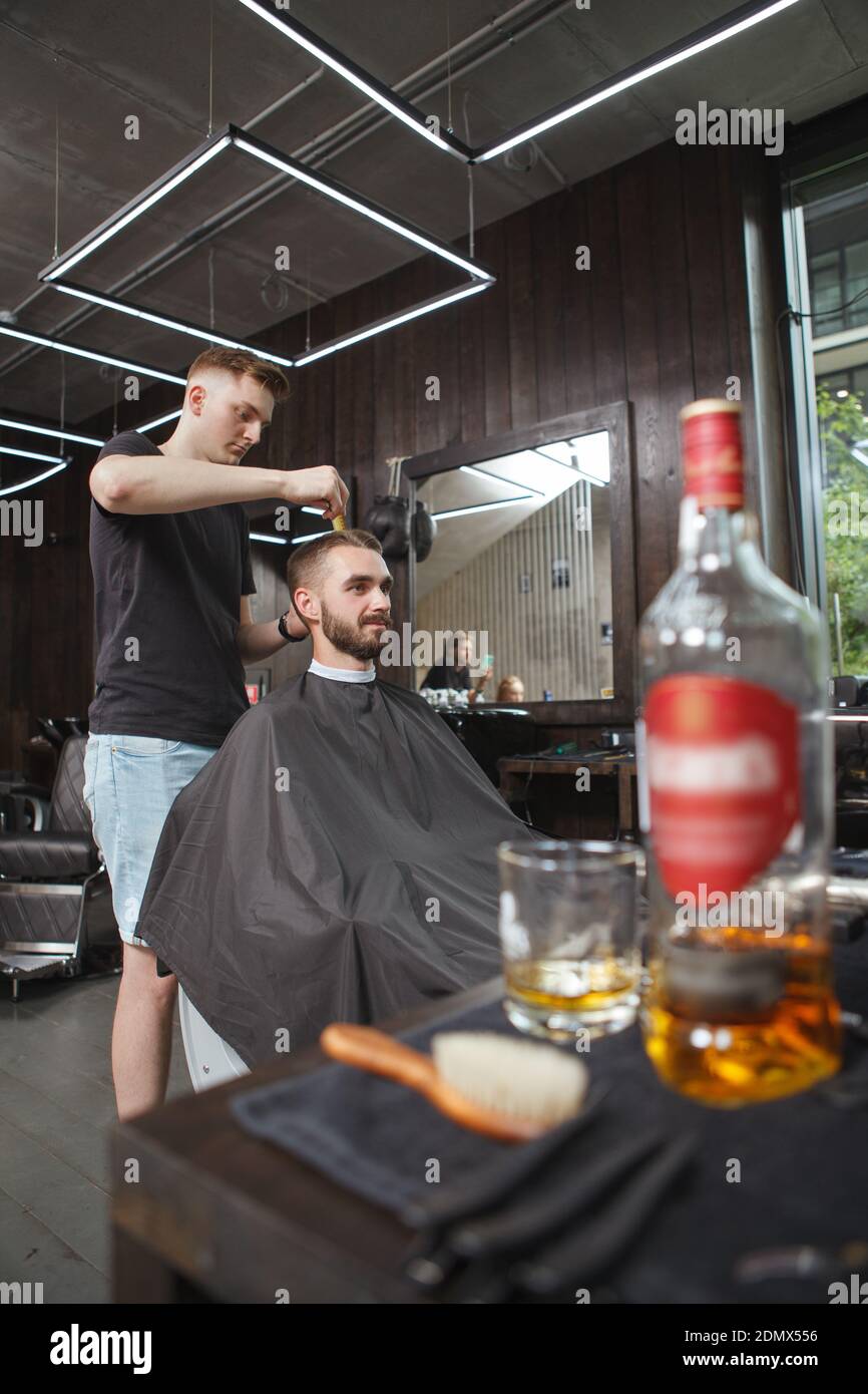 Vertical shot of a professional barber giving a new hairstyle to his ...