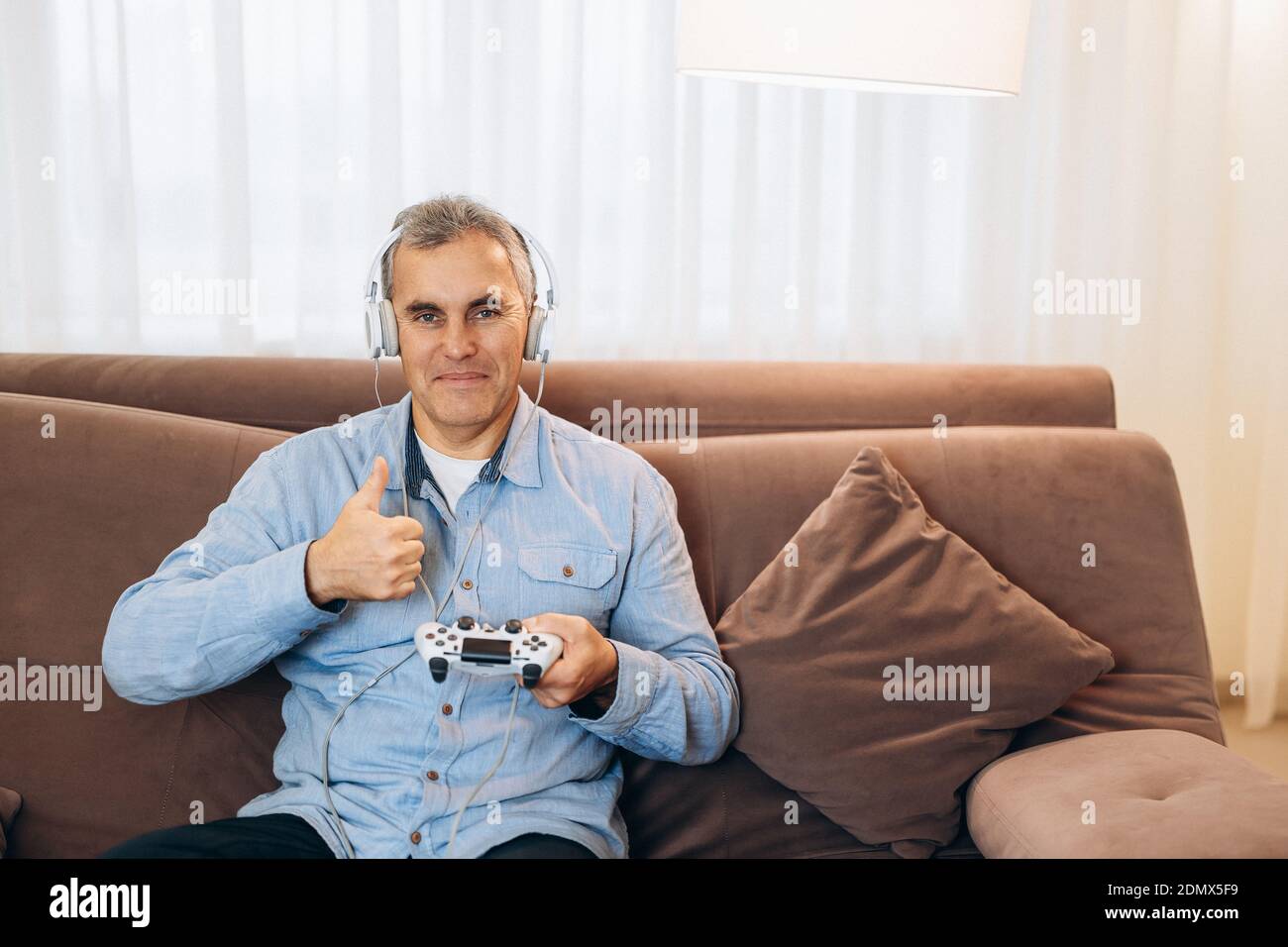 Mature gamer man playing video game using joystick and headphones happy ...