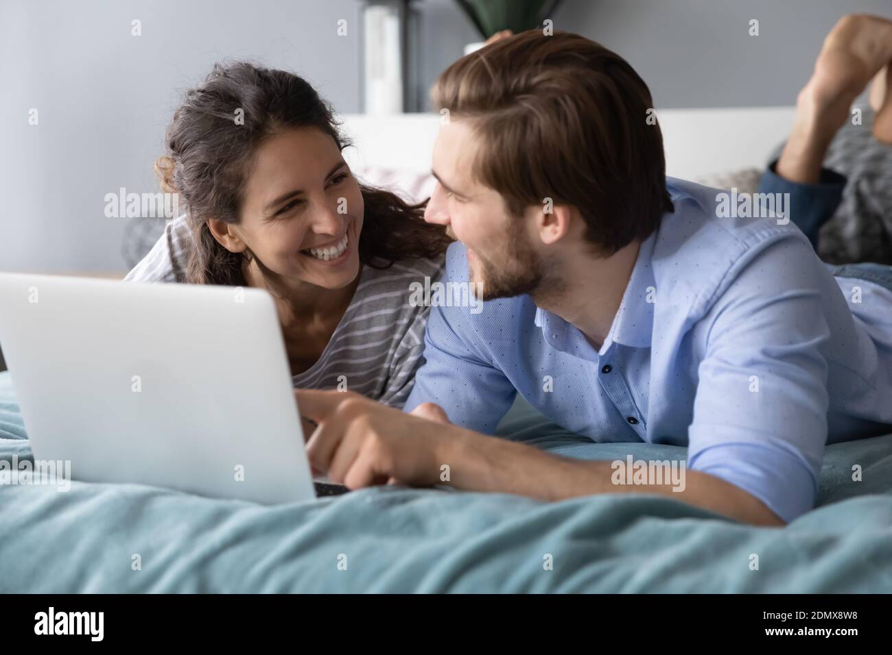 Happy couple relax in bed using computer together Stock Photo - Alamy