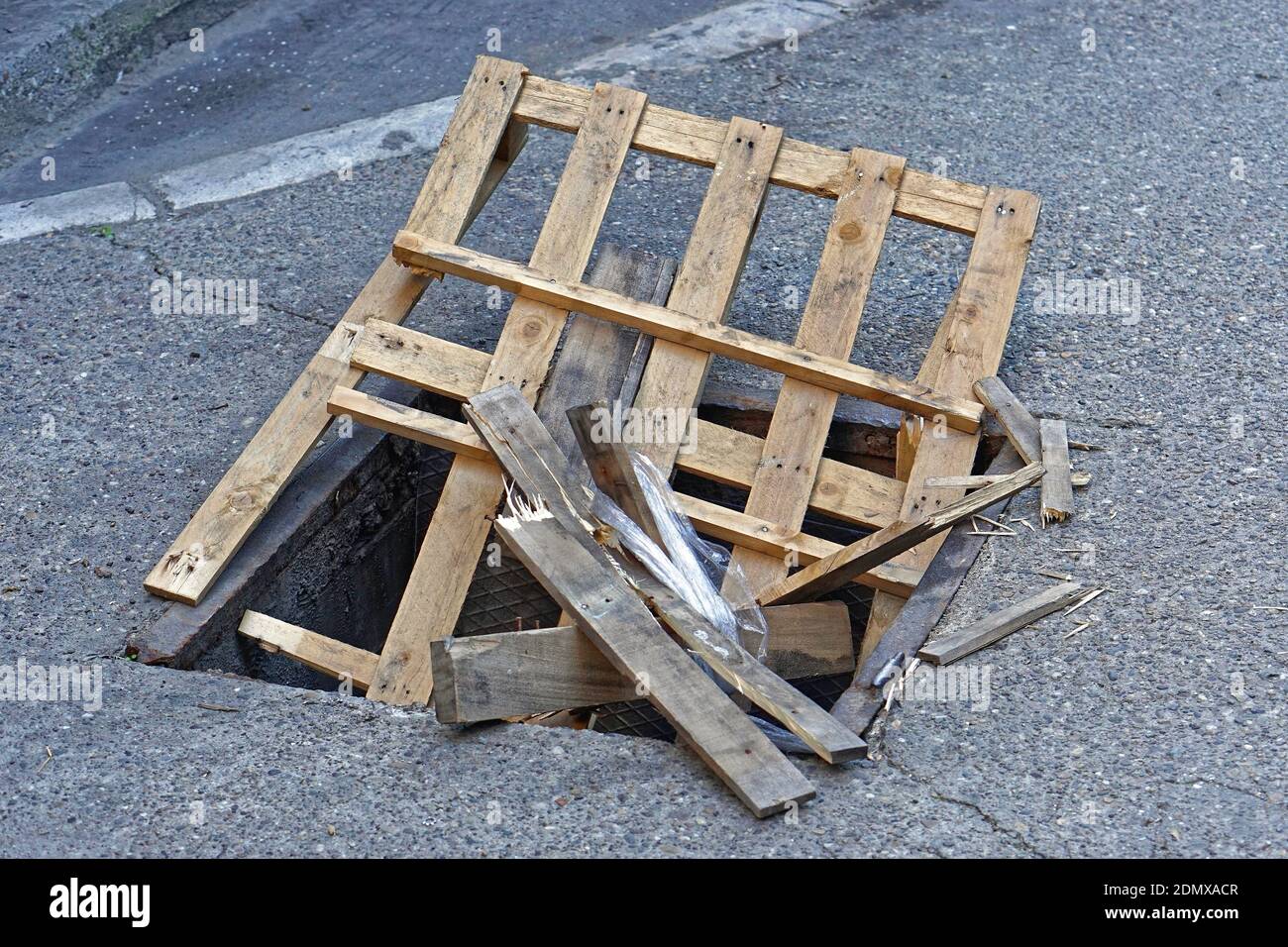 Broken cargo pallet at open manhole shaft danger Stock Photo - Alamy